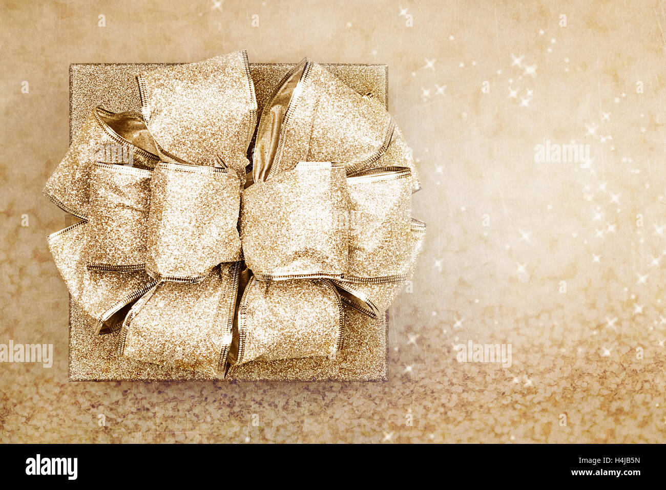 Beautiful gold gift with bow against a magical golden background with ...