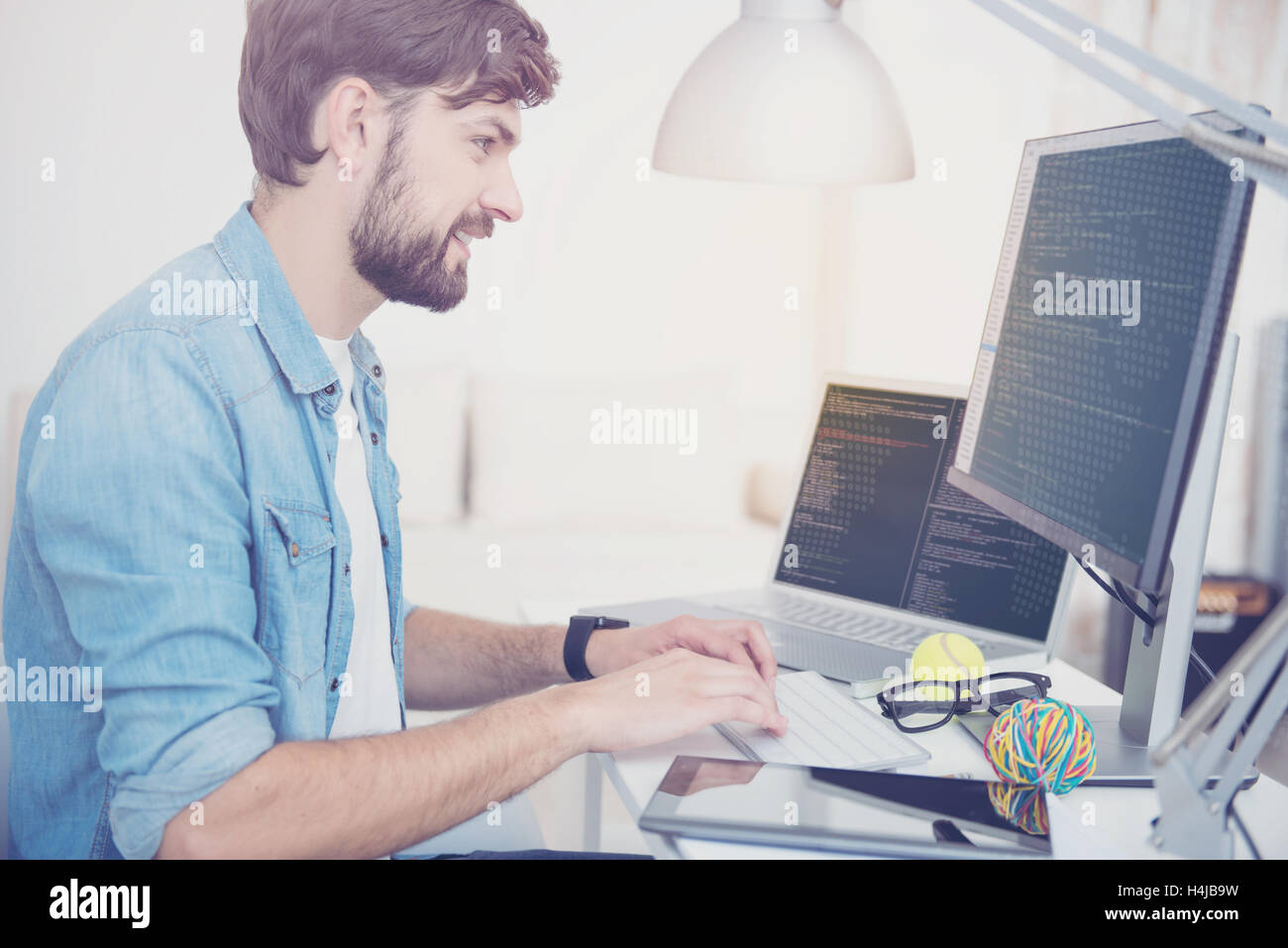 Smiling man programming in a cozy office Stock Photo - Alamy