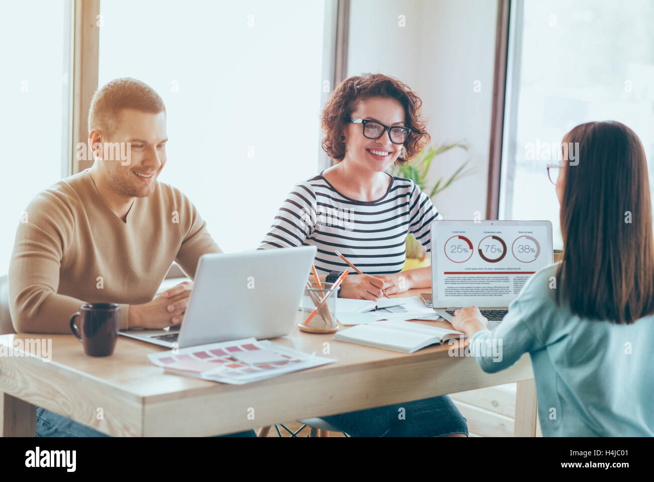 Positive smiling colleagues working at the table Stock Photo - Alamy