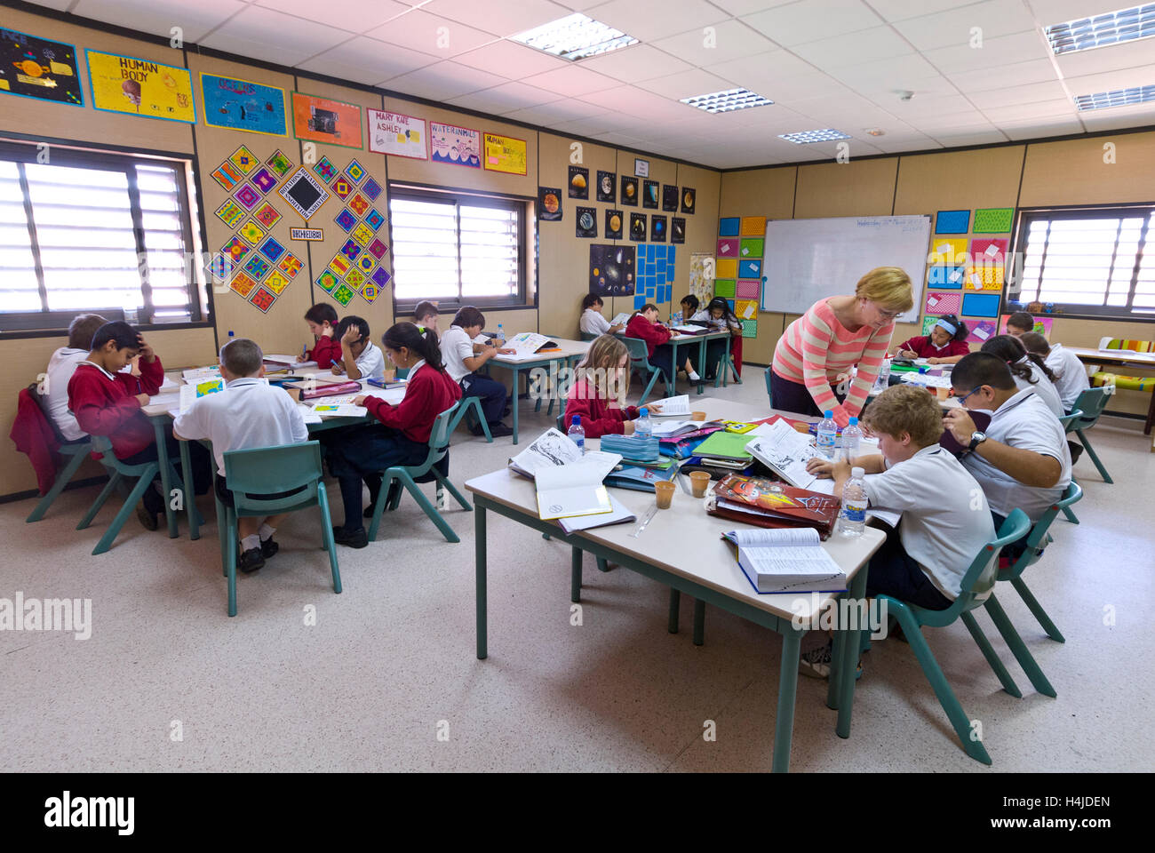 Junior school children with female teacher concentrate on their studies ...