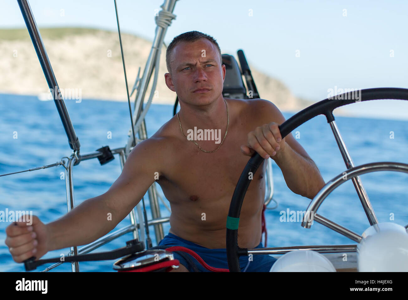 Young man skipper steers wheel the sailing yacht boat. Vacation ...