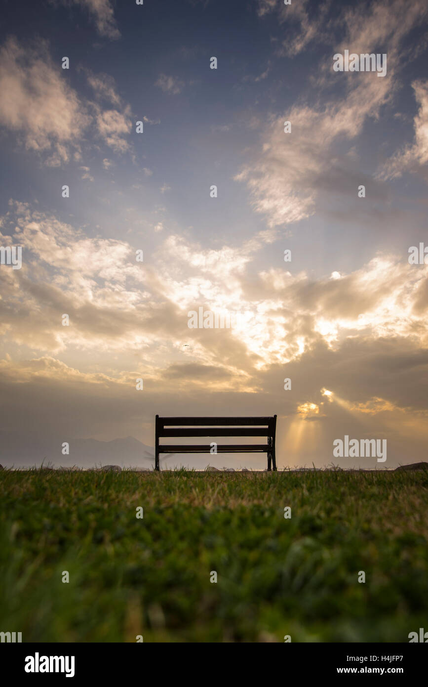 An empty bench set against a sunset sky Stock Photo - Alamy