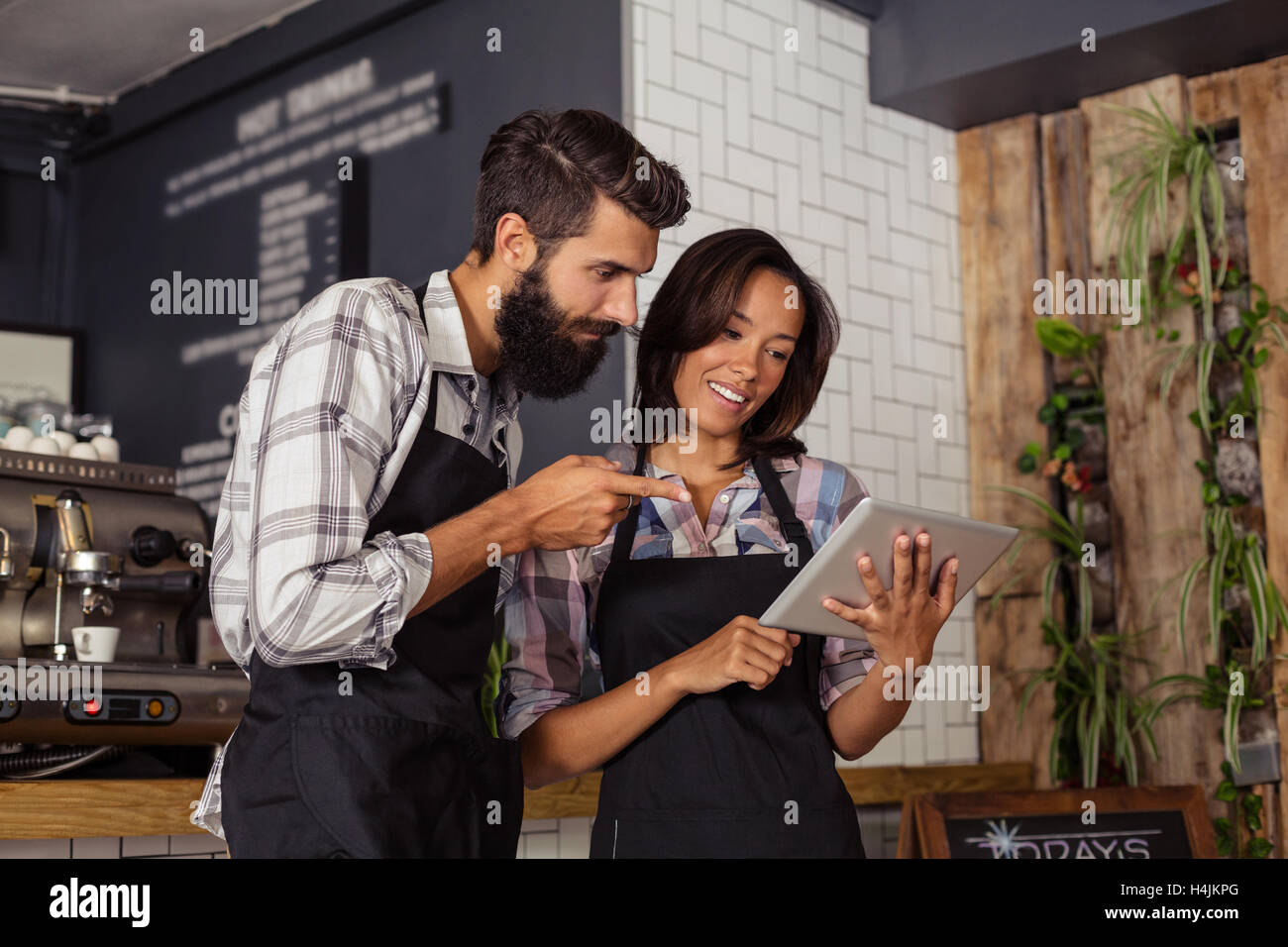 Smiling waiter and waitress interacting while using digital tablet ...