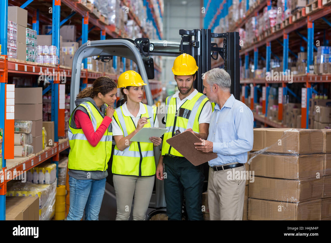 Warehouse manager and co-workers discussing over clipboard Stock Photo ...