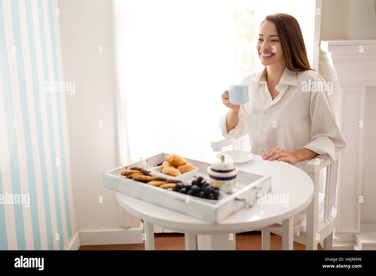 Beautiful woman enjoying morning tea wearing shirt Stock Photo - Alamy