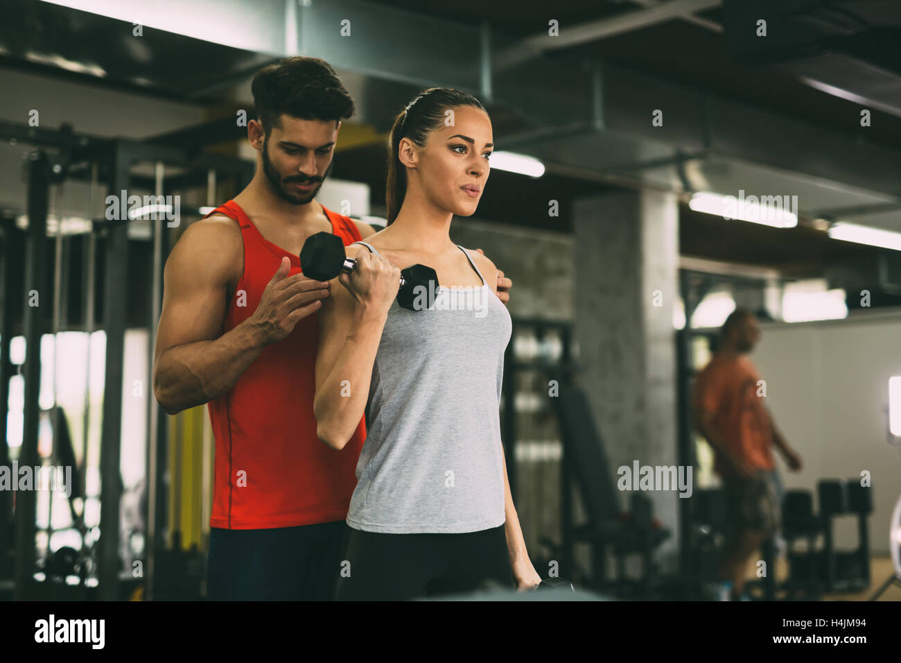 Personal trainer instructing trainee in gym Stock Photo - Alamy