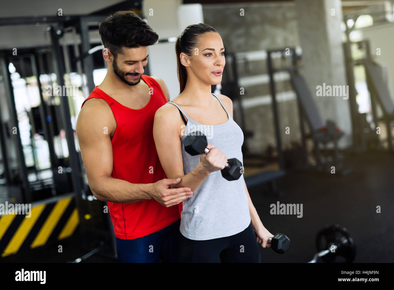 Personal trainer instructing trainee in gym Stock Photo - Alamy