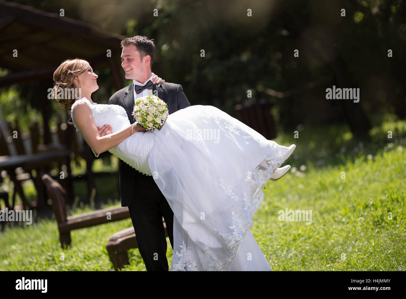 Groom carrying bride outdoors and smiling Stock Photo - Alamy