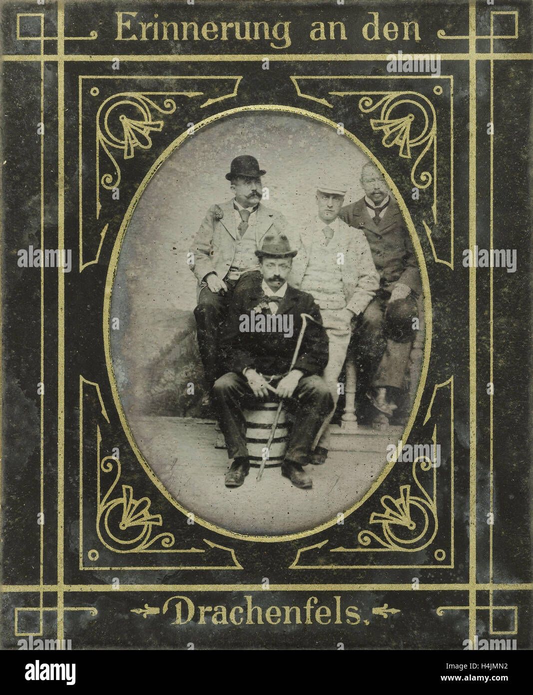Portrait of four men standing and sitting on a ton and a balustrade ...