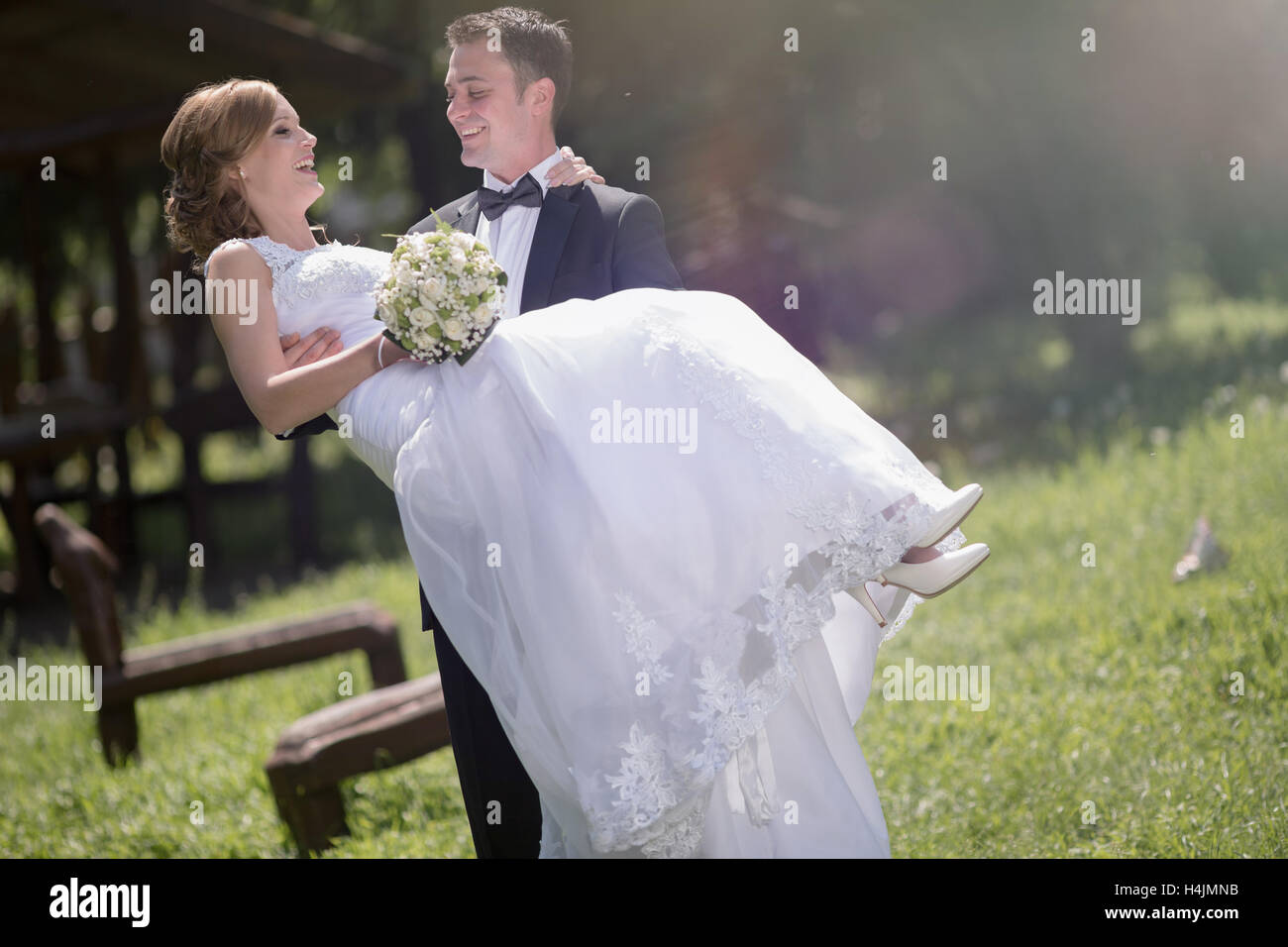 Groom carrying bride outdoors and smiling Stock Photo - Alamy