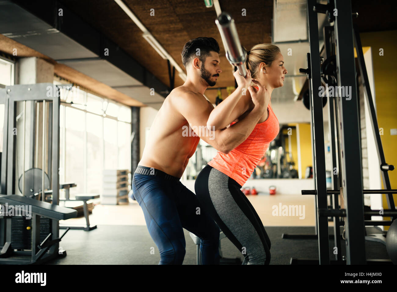 Personal trainer helping woman in gym Stock Photo - Alamy