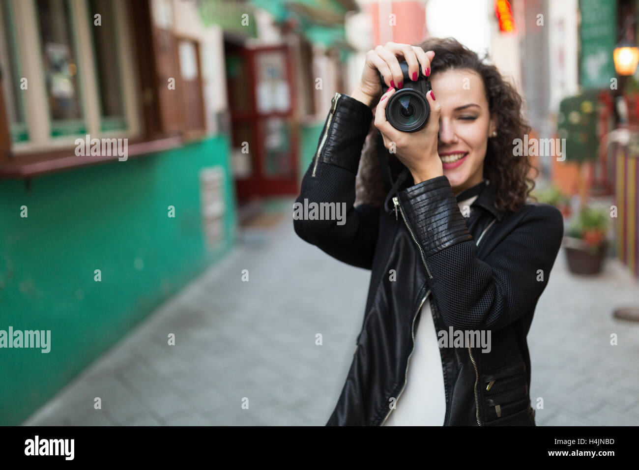 Beautiful woman taking pictures outdoors and smiling Stock Photo - Alamy
