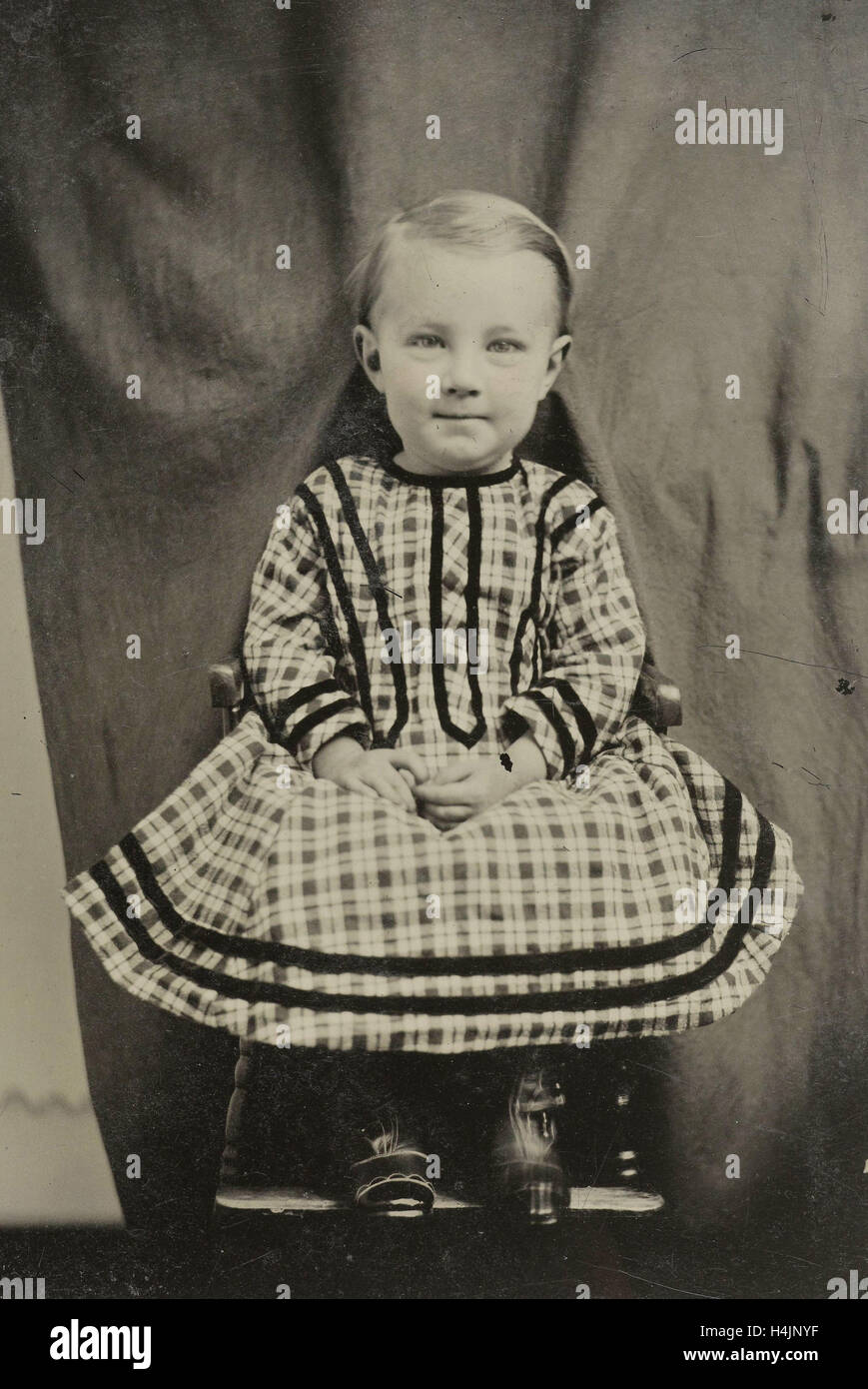 Portrait of a child sitting on a chair in a studio setting Stock Photo ...