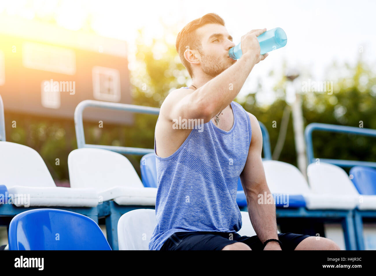 Sports man drinking water after exercising on outdoors stadium Stock ...