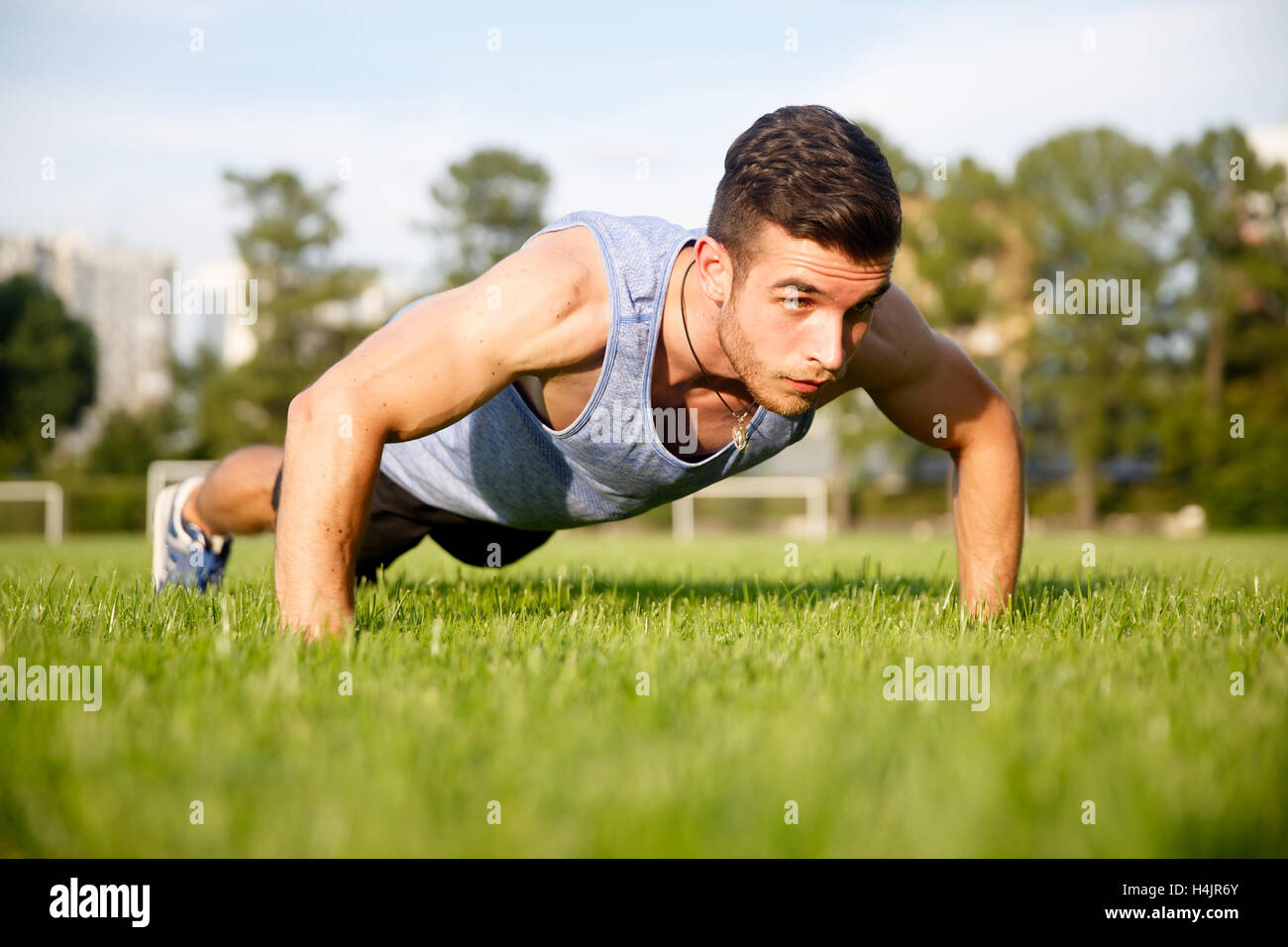 Muscular young guy doing push-ups in park on lawn Stock Photo - Alamy