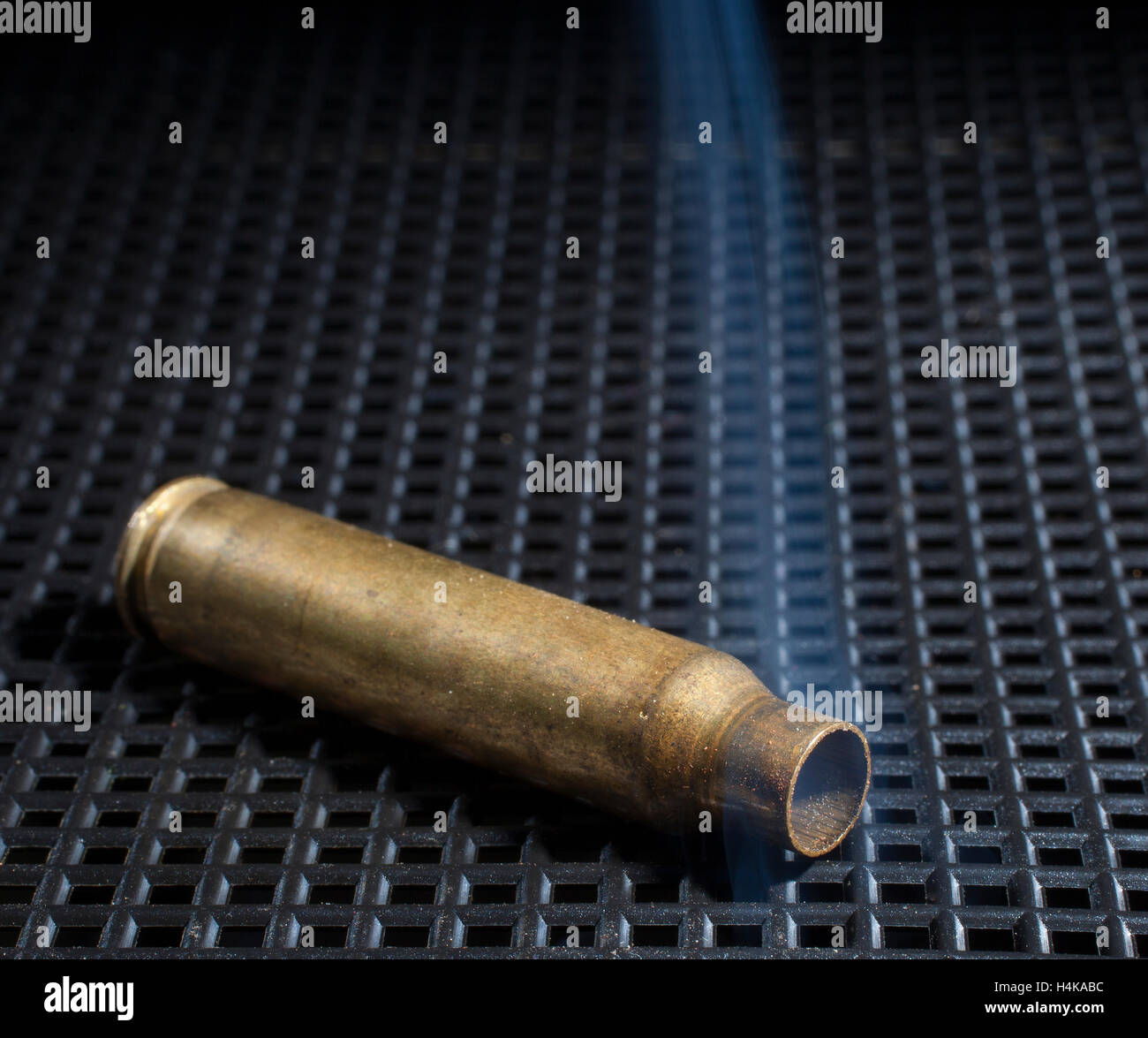 Empty rifle brass on a black grate that is smoking Stock Photo - Alamy
