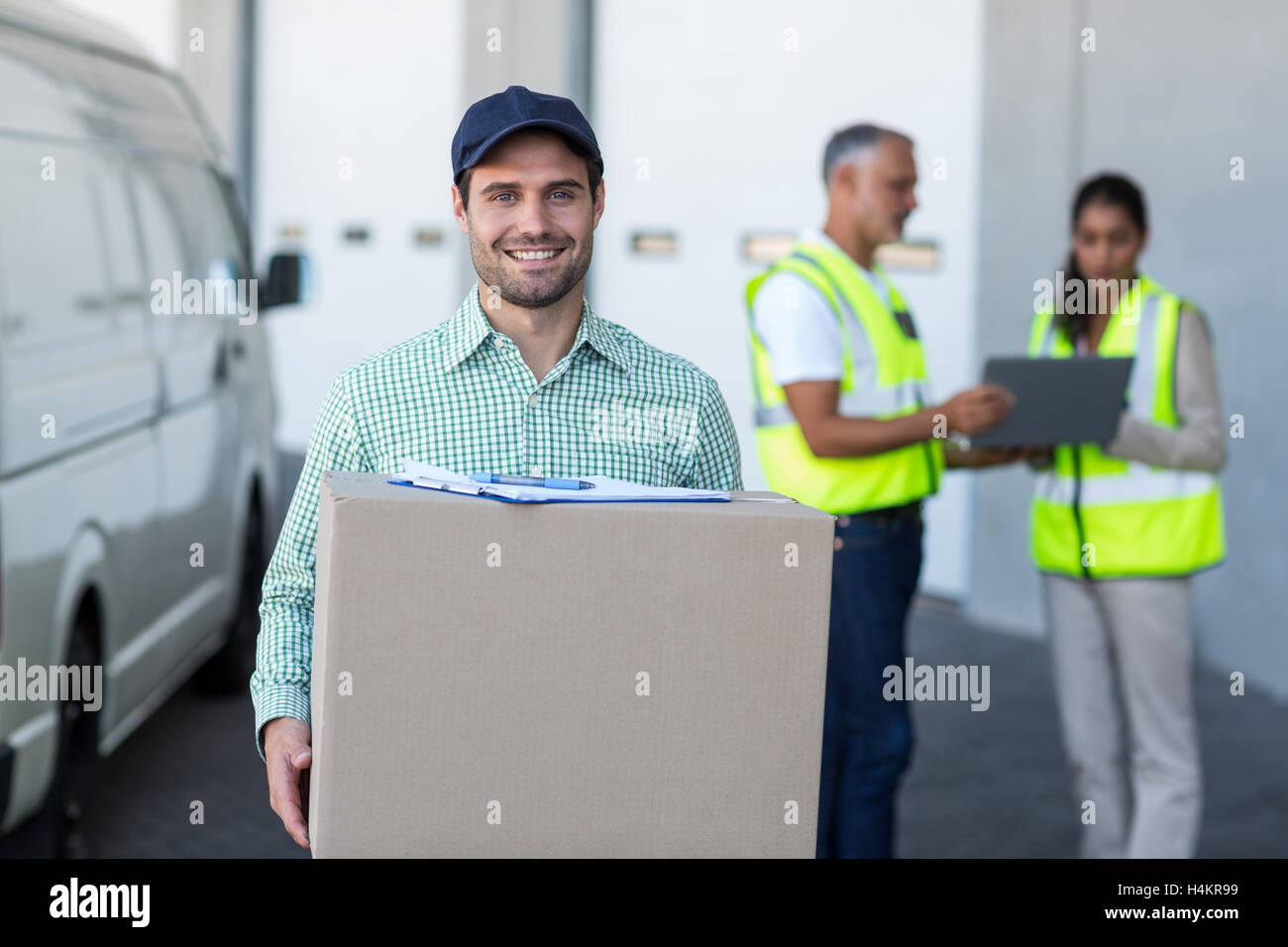 Portrait of delivery man carrying cardboard box Stock Photo - Alamy