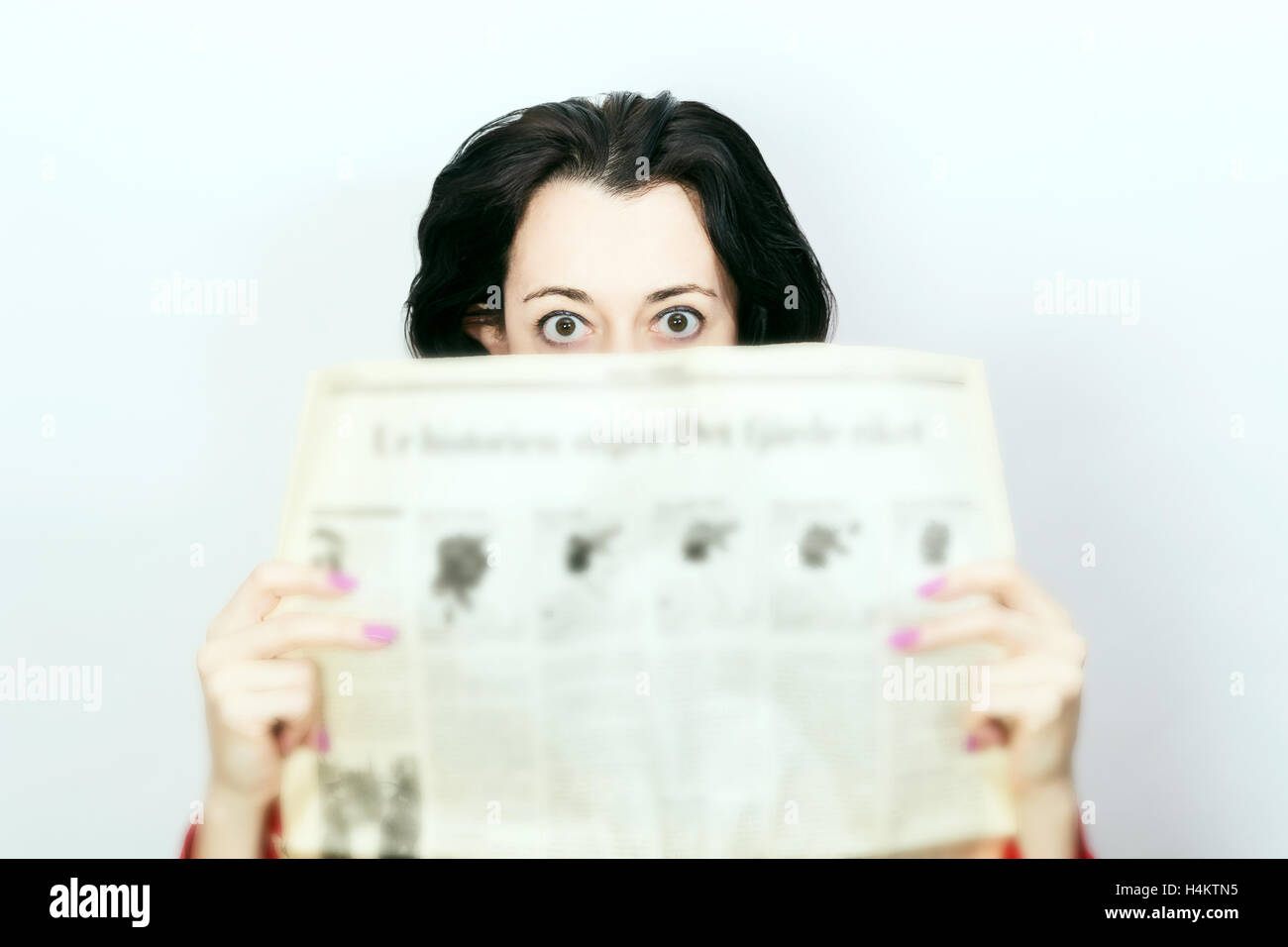Beauty brunette woman with newspaper in shock Stock Photo - Alamy