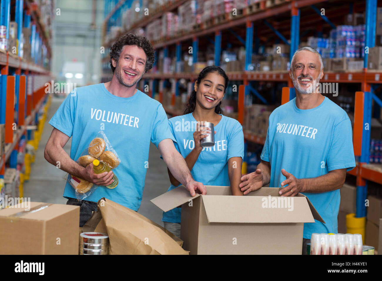 Three volunteers packing eatables in cardboard box Stock Photo - Alamy