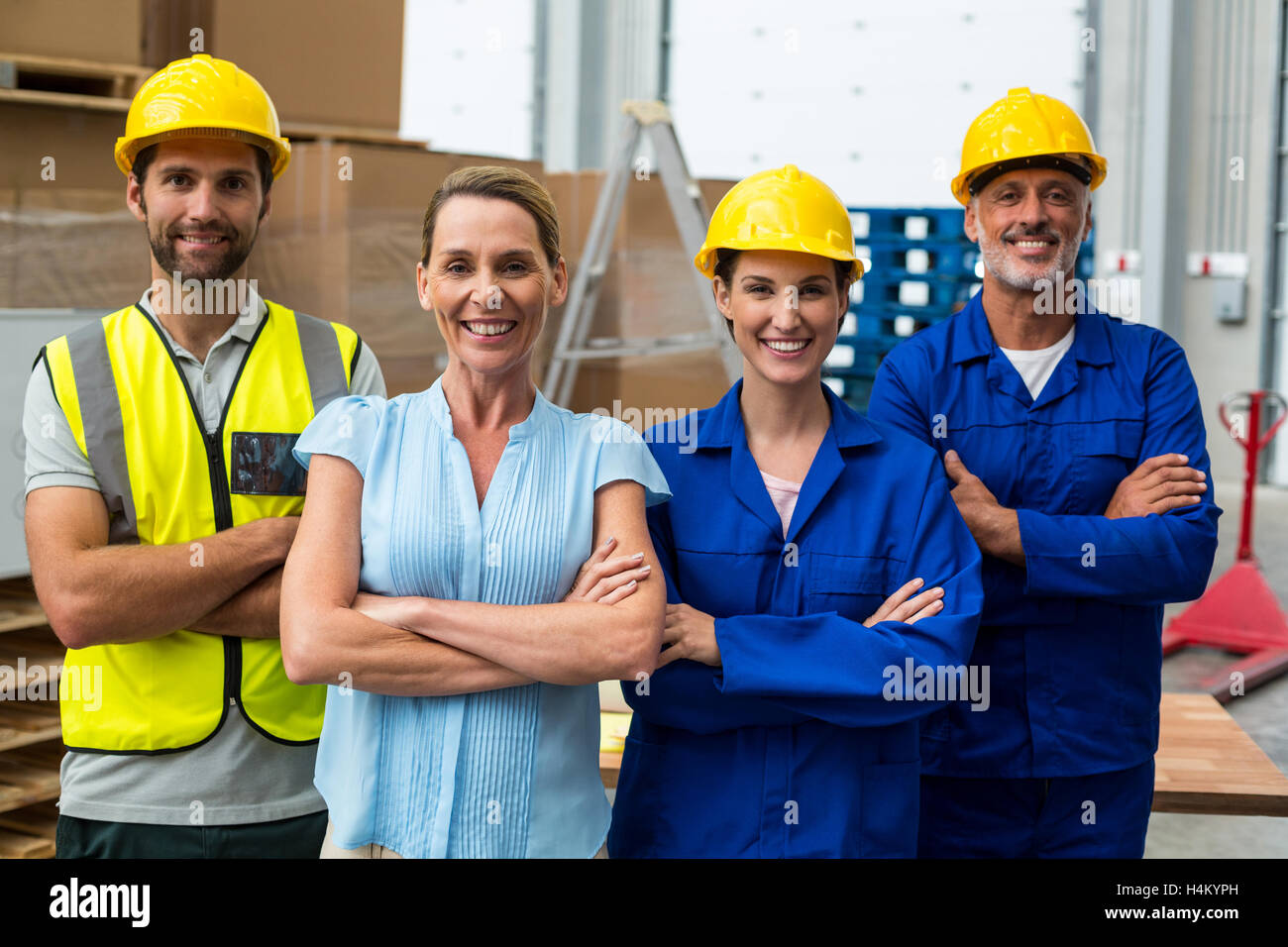 Portrait of warehouse manager and worker standing together with arms ...
