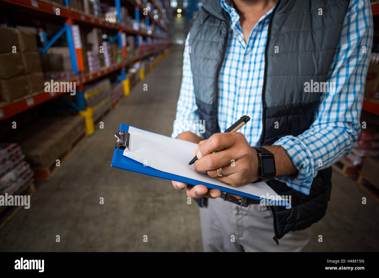 Mid section of warehouse worker writing on clipboard Stock Photo - Alamy