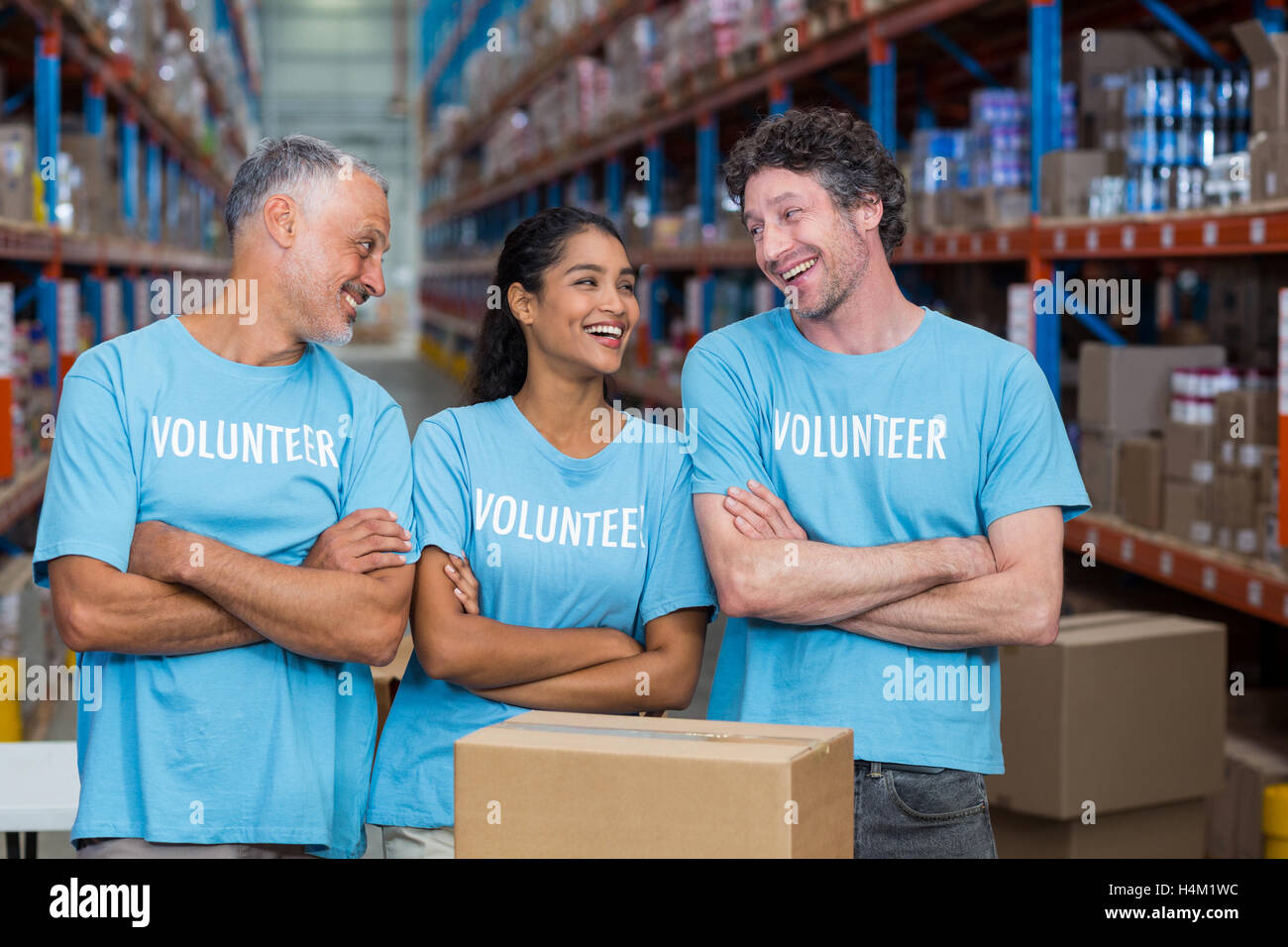 Three happy volunteers standing with arms crossed Stock Photo - Alamy