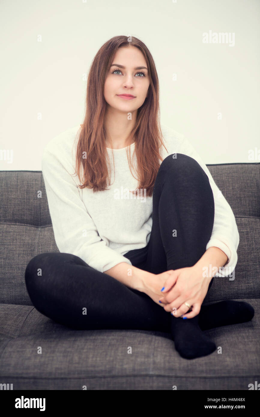 young beautiful woman sitting on couch and smiles Stock Photo - Alamy