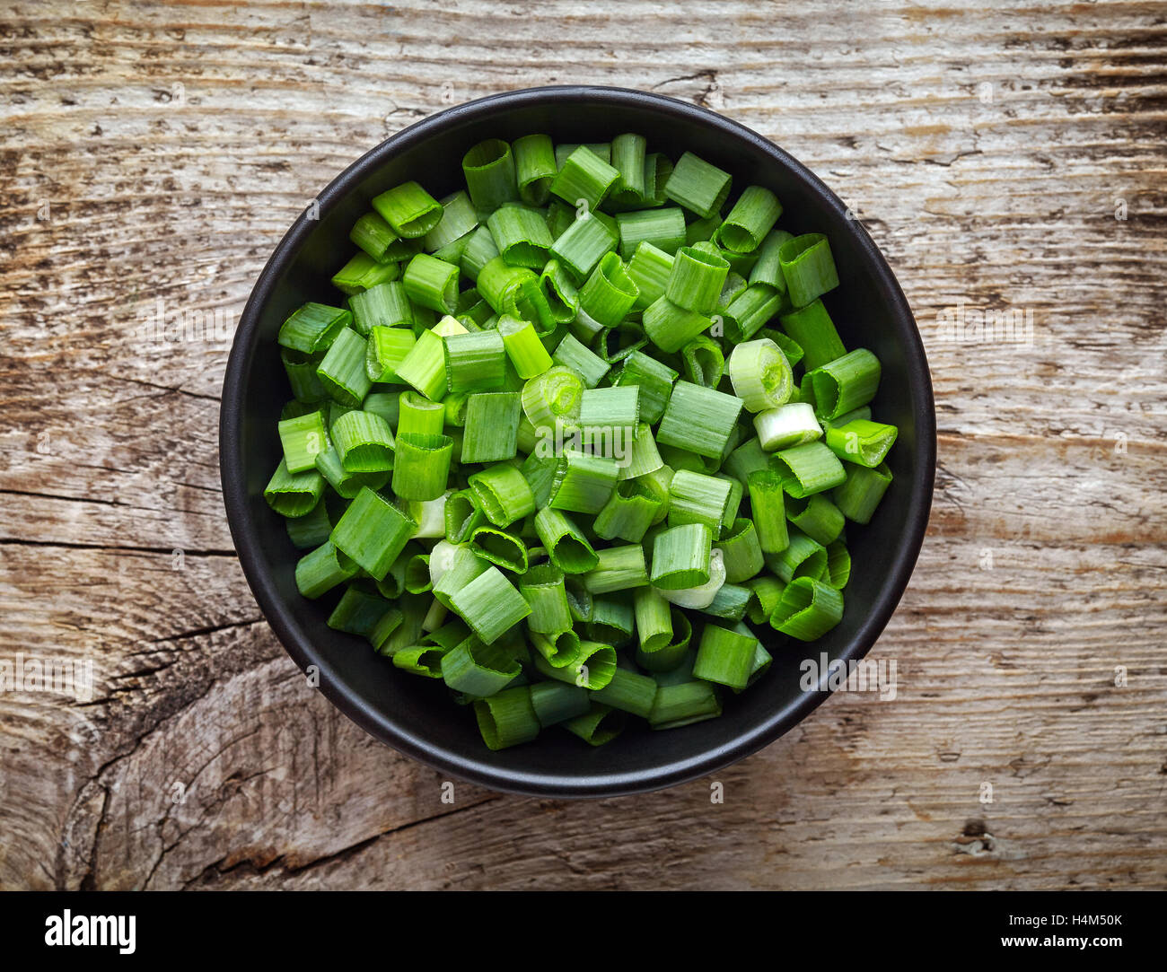 Bowl of chopped spring onions on wooden table, top view Stock Photo - Alamy