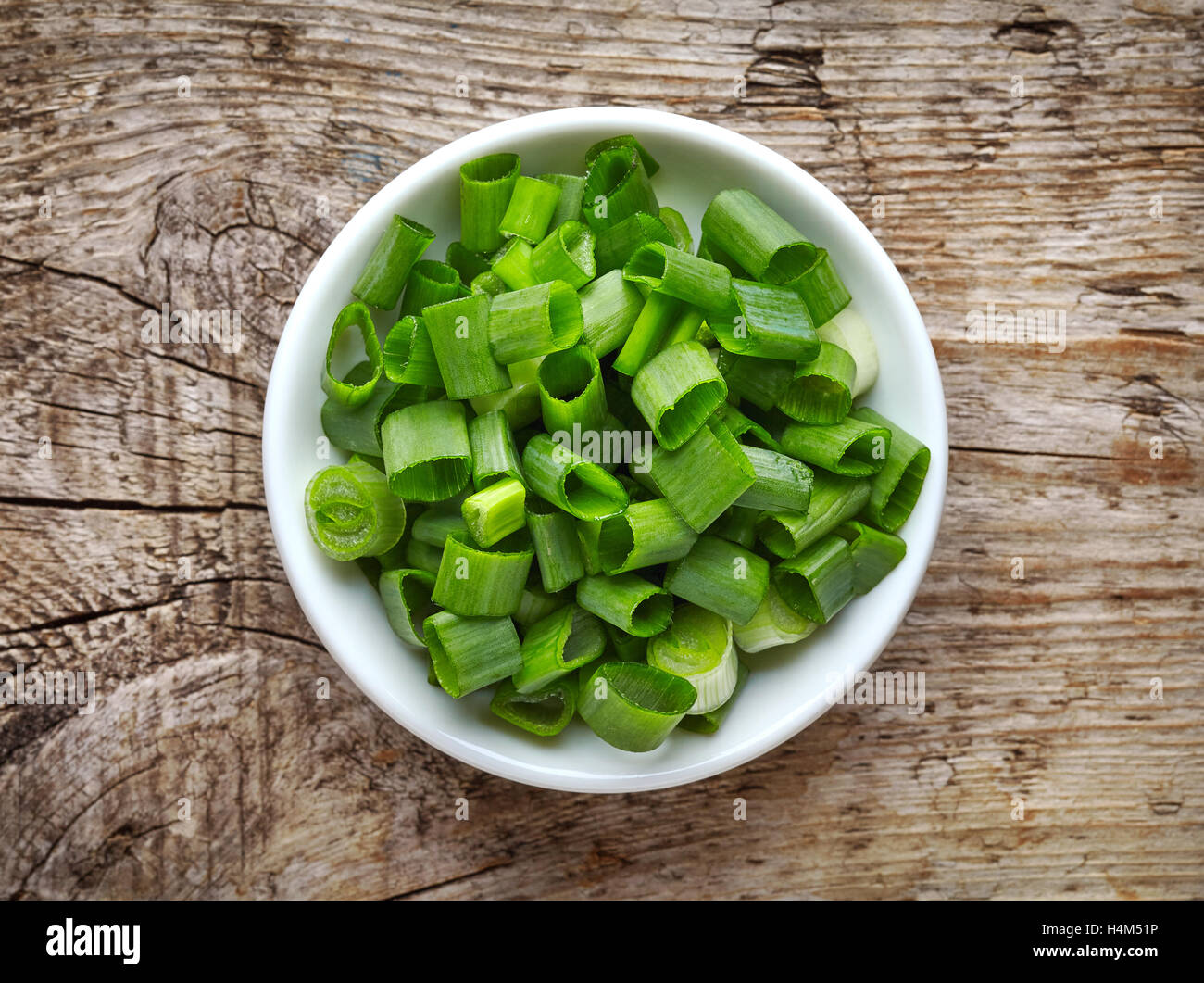 Bowl of chopped spring onions on wooden table, top view Stock Photo - Alamy