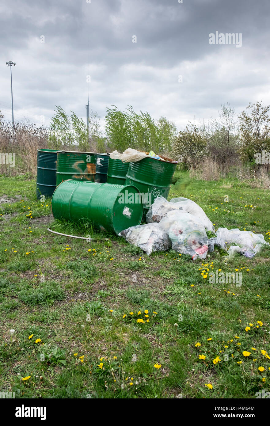 An overturned trash can with full plastic bags in front in a park in ...