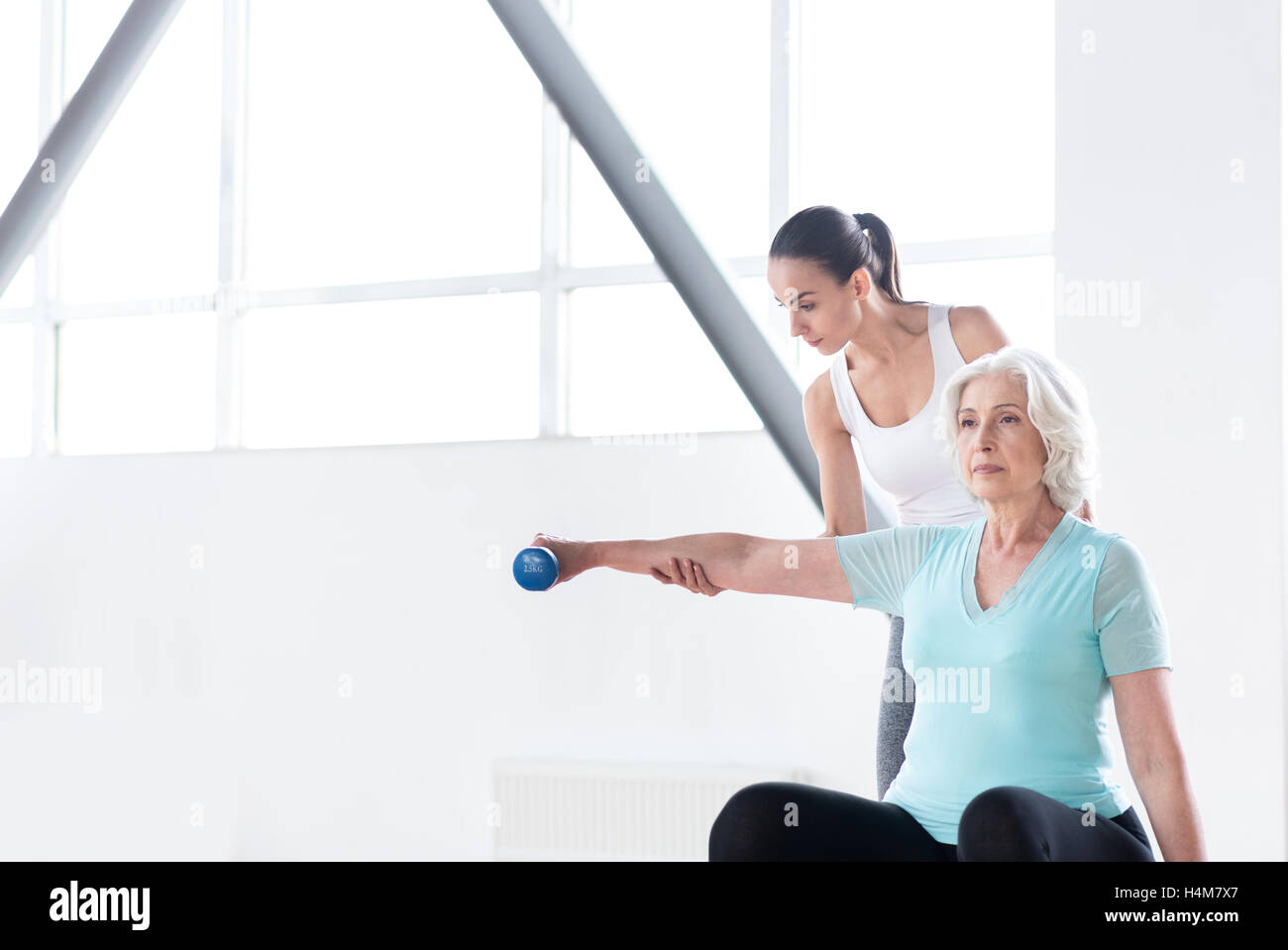 Serious hard working woman exercising with a dumbbell Stock Photo - Alamy