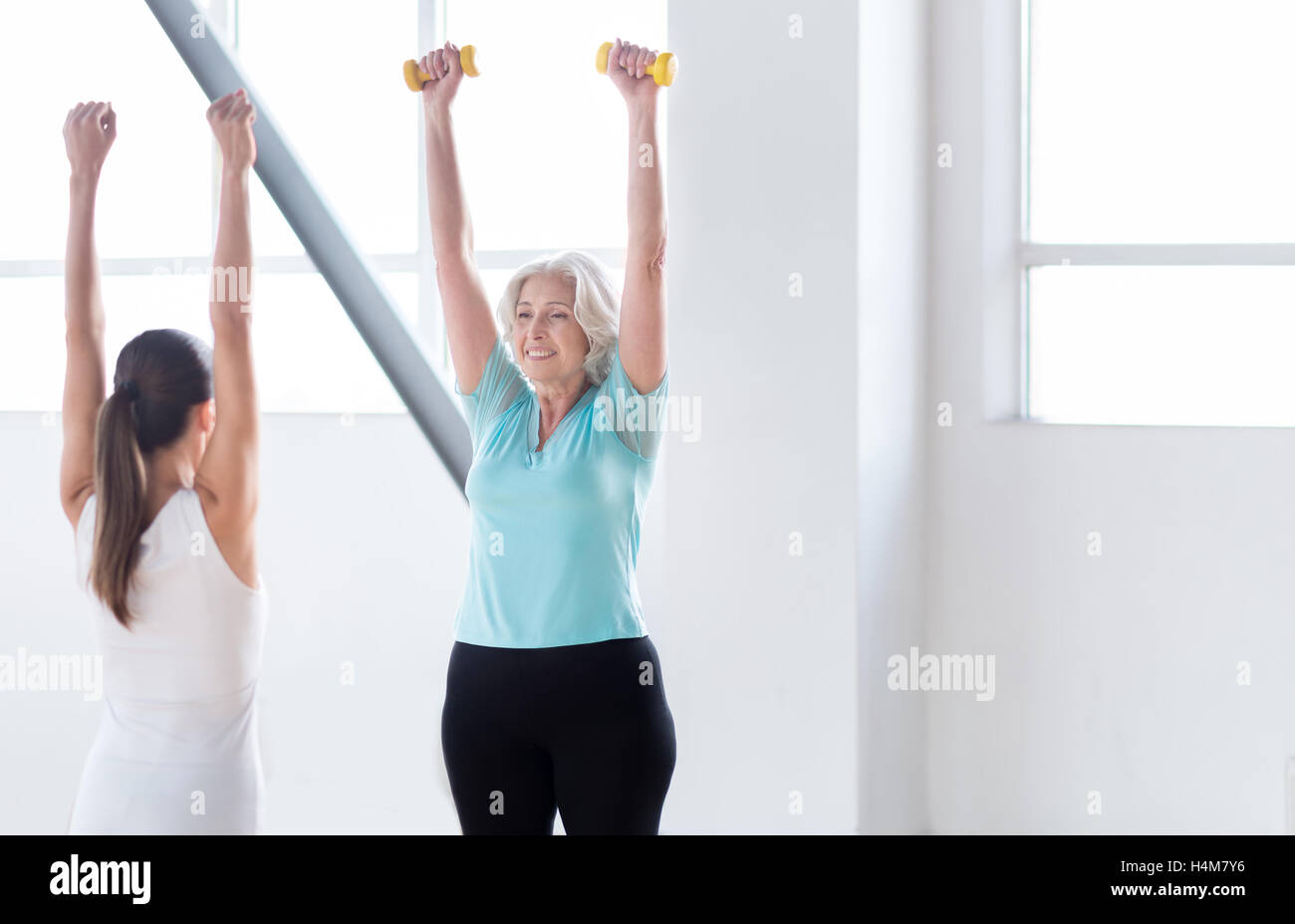 Athletic slim woman holding small dumbbells up Stock Photo - Alamy