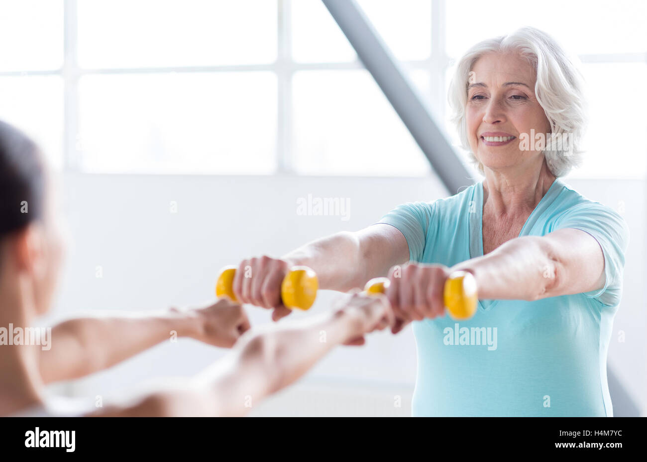 Pleasant old woman working out with small rubber dumbbells Stock Photo ...