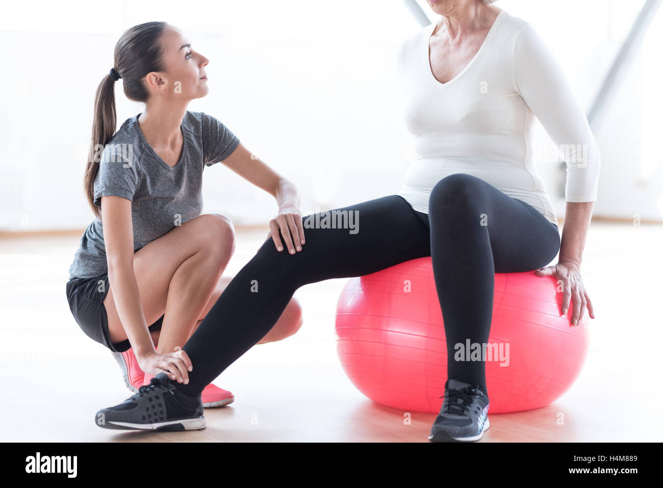 Experienced pleasant coach helping to do the exercise Stock Photo - Alamy