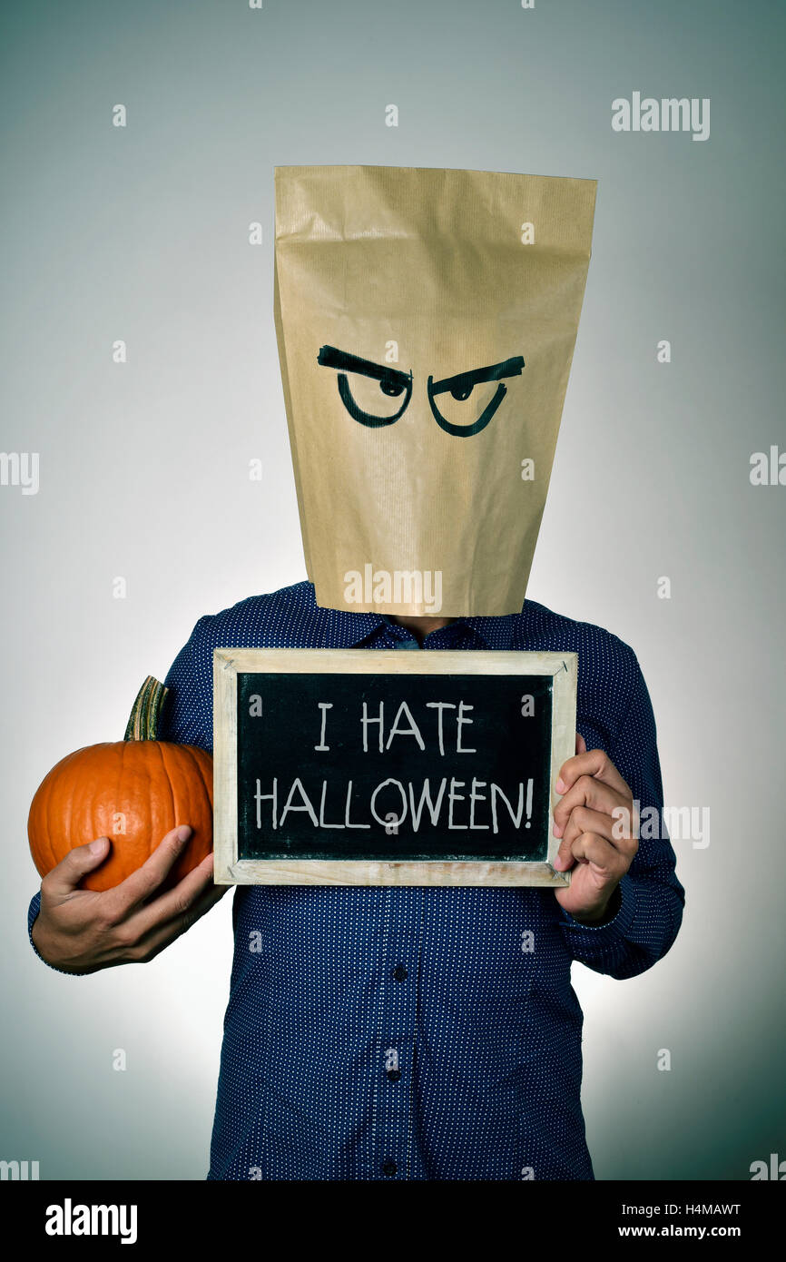 a young man with a paper bag in his head with a funny face, holds a ...