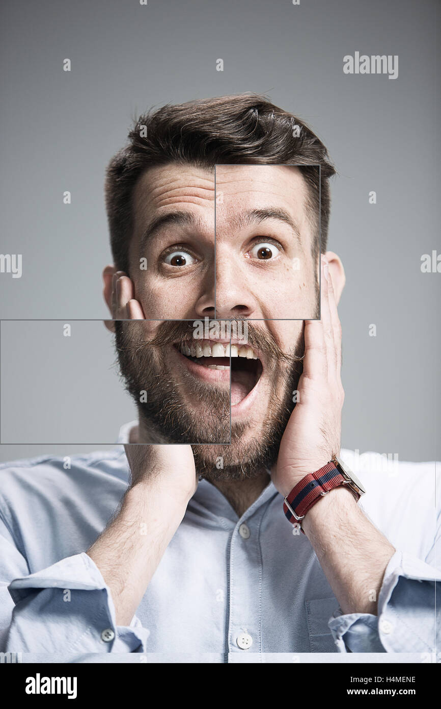 Portrait of young man with shocked facial expression over gray ...