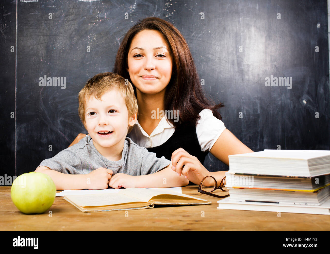little cute boy with young teacher in classroom studying at blac Stock ...