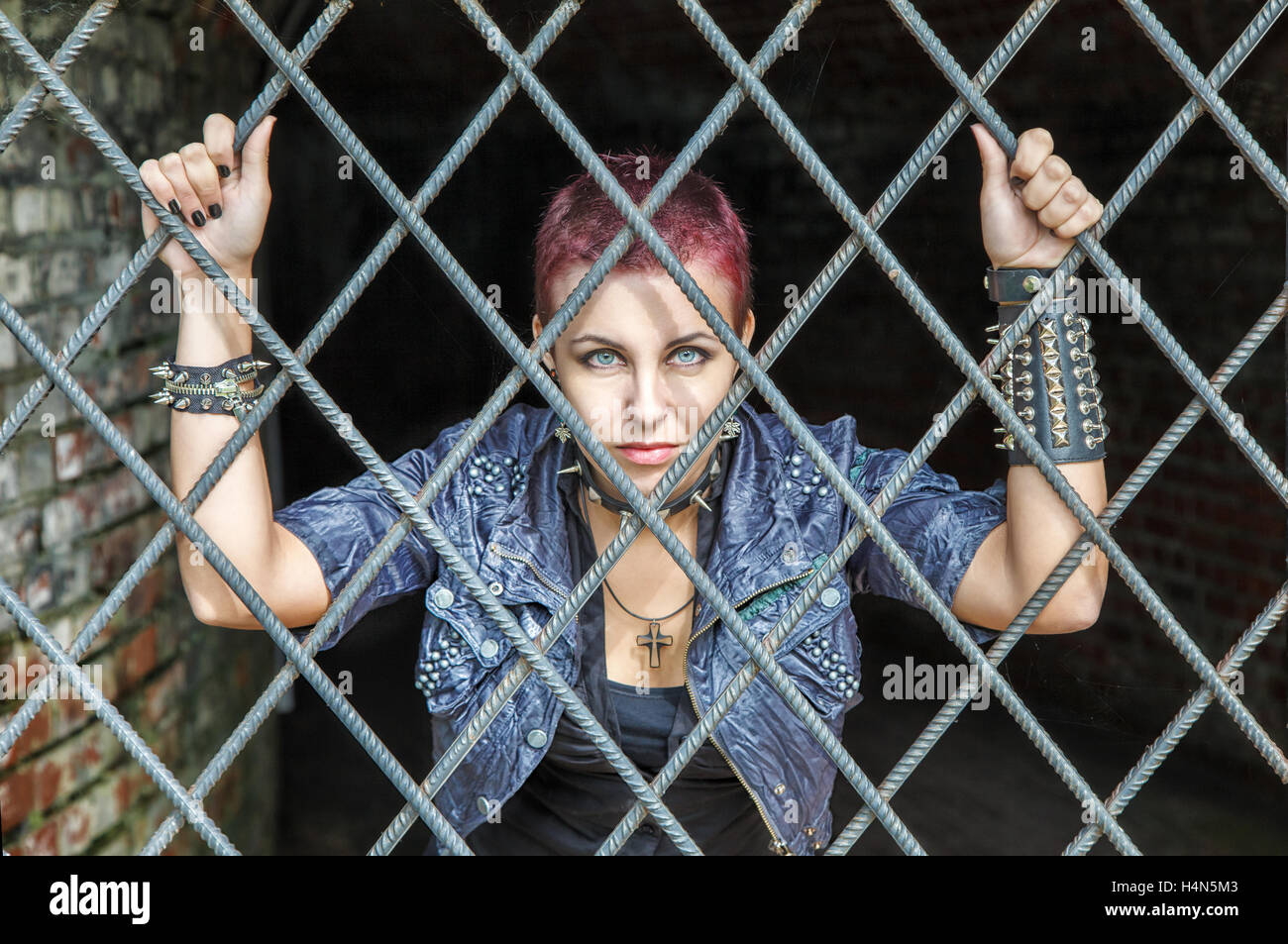 young pretty punk girl standing behind bars Stock Photo - Alamy