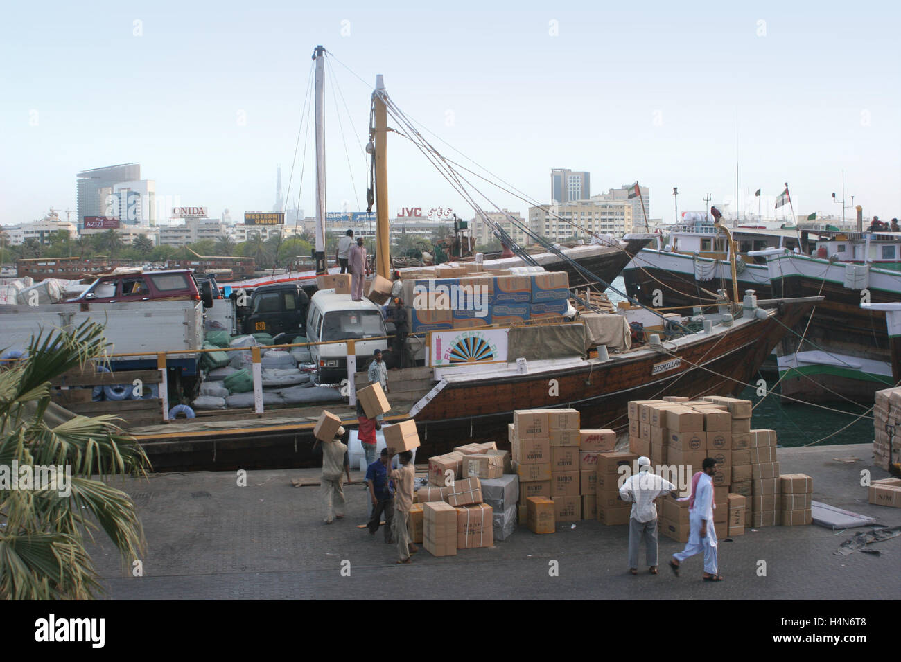 Boxes are manually loaded onto a traditional timber cargo ship moored ...