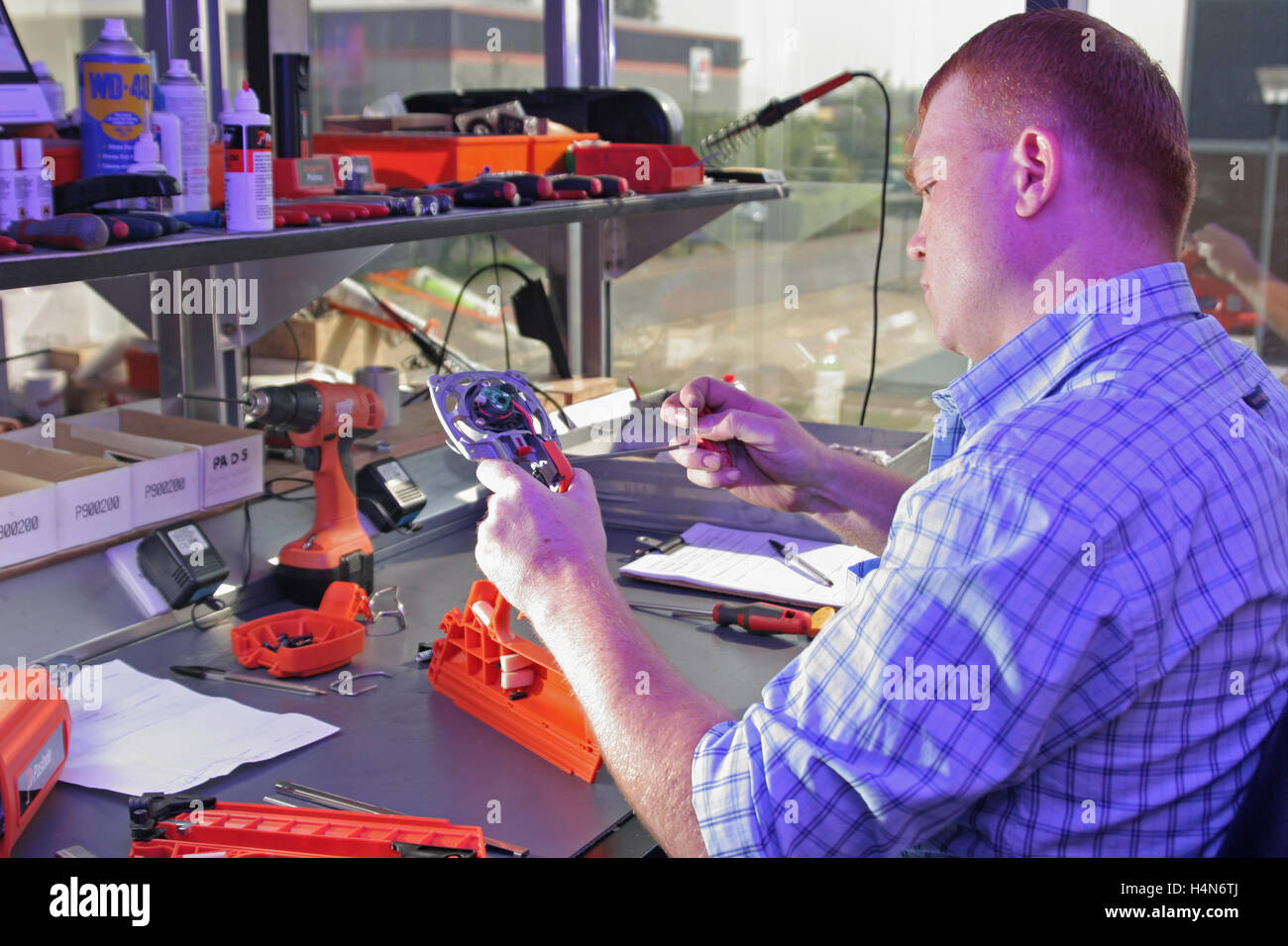 An engineer repairs and services power tools at a workbench in a modern ...