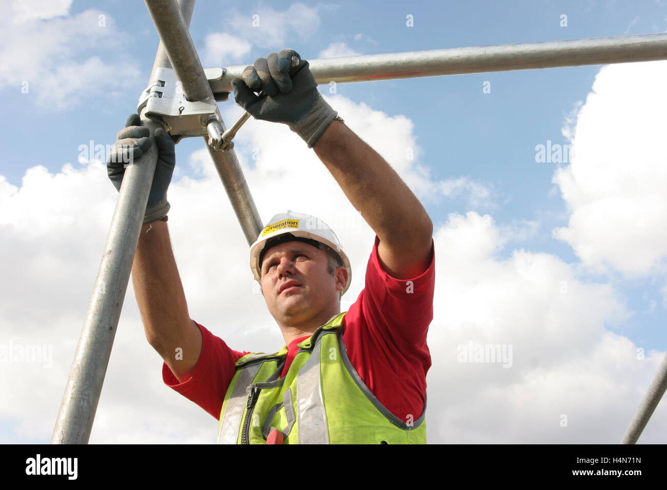 A scaffolder tightens a fitting whilst assembling traditional tube and ...