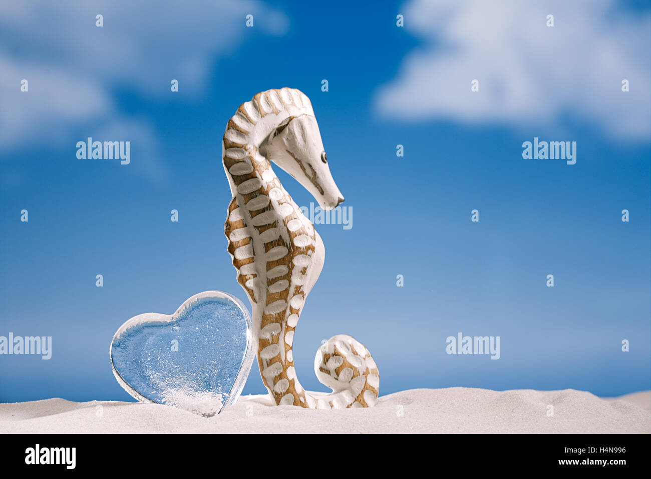 seahorse with glass heart on white sand beach, ocean, sky and seascape ...
