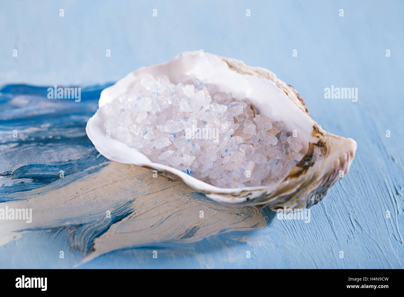 Blue persian sea salt in sea shell oyster on blue abstract painted ...
