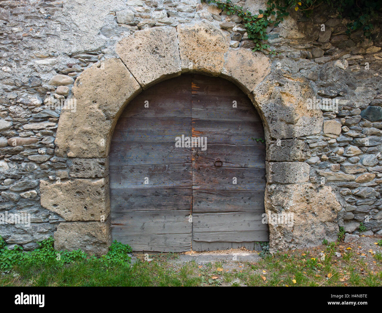 Ancient arched entrance with wooden door in a medieval stone wall Stock ...