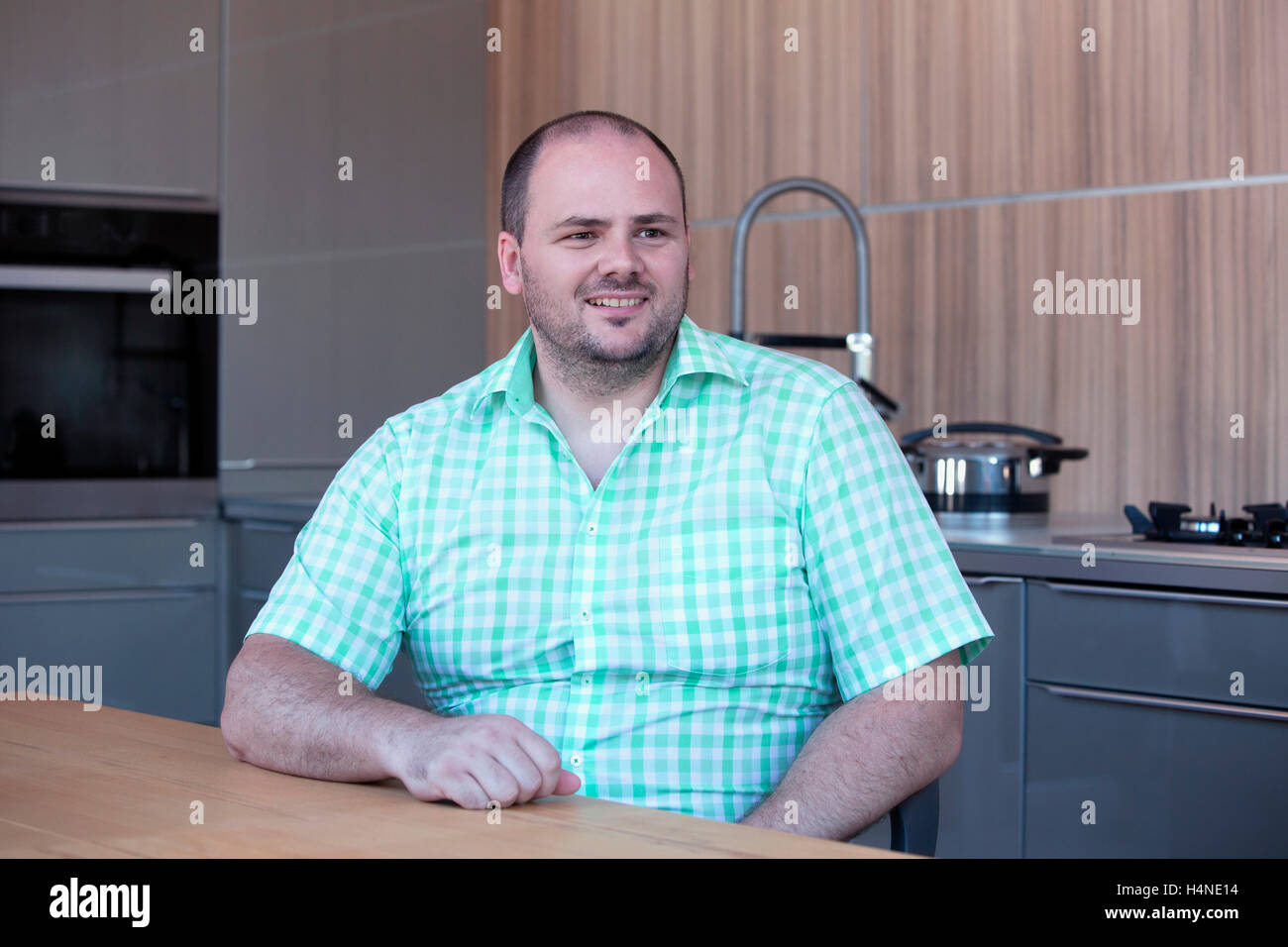 portrait of overweight man sitting at kitchen table and smiles Stock ...