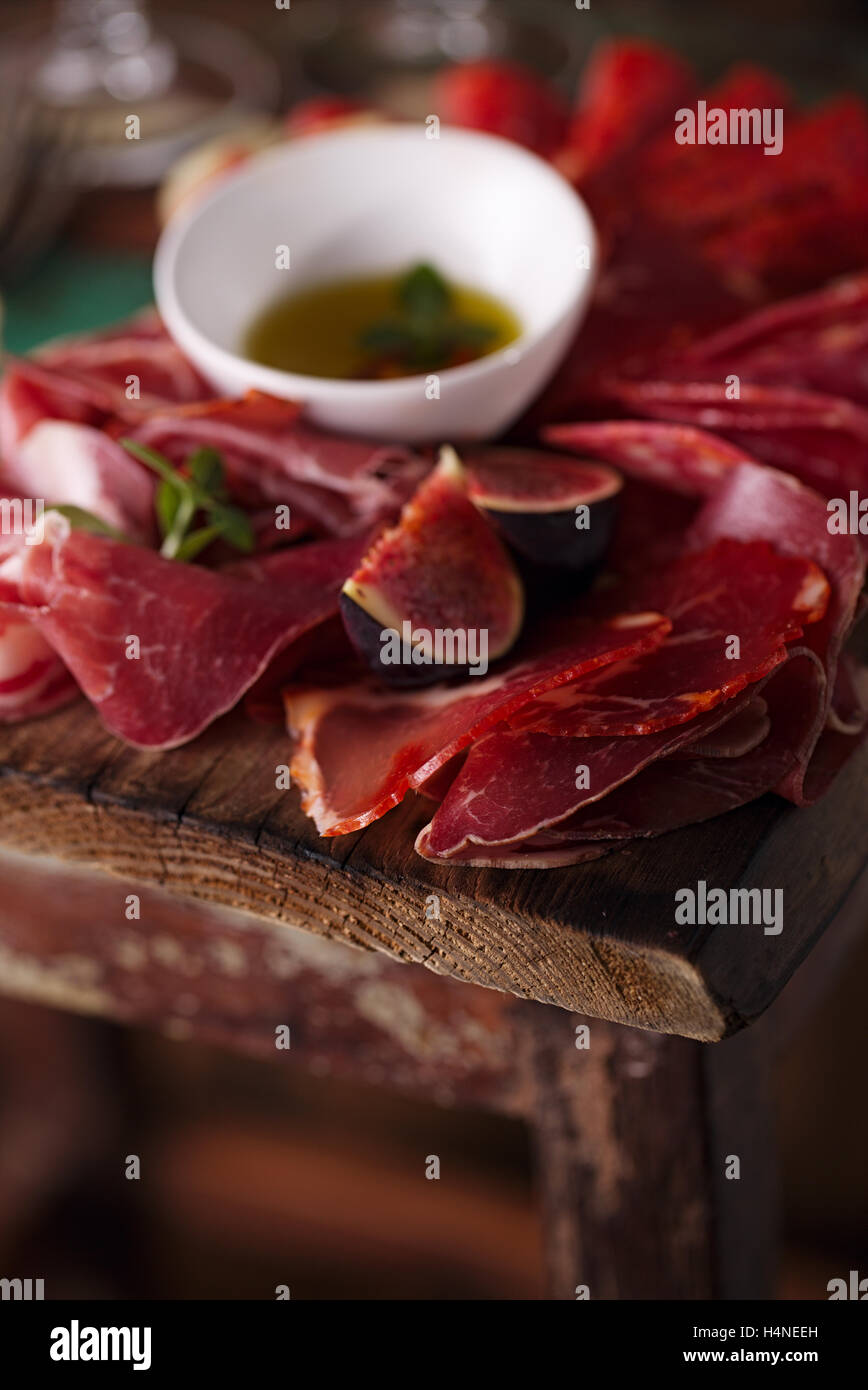 Cured Meat and olive oil on textured old wooden stool background Stock ...