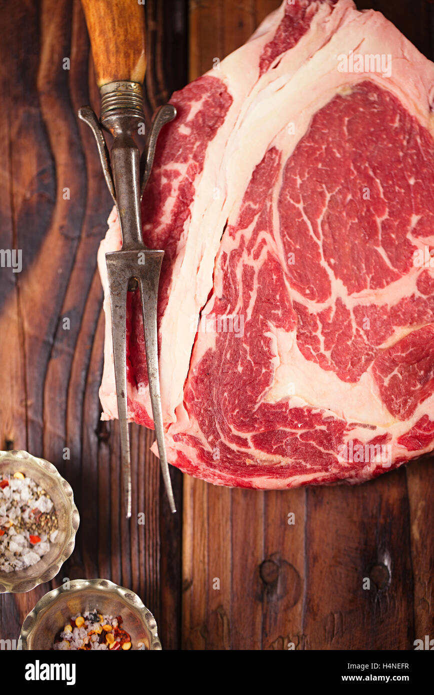 raw beef Ribeye steak on wooden table with vintage carving fork , knife ...
