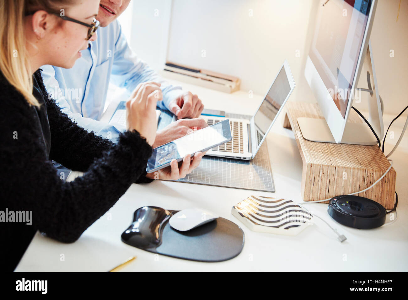 Two people at a workstation, working together on a tablet, laptop ...