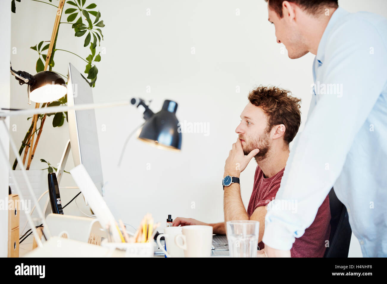 Two men working together, looking at a computer screen Stock Photo - Alamy
