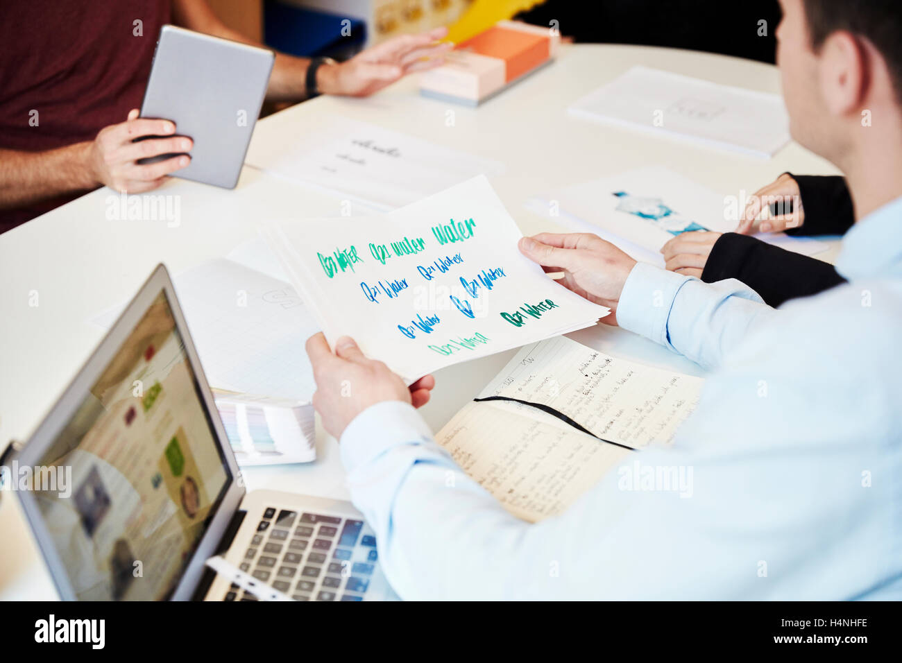 A man holding paper with printed logos and lettering Designers at work ...